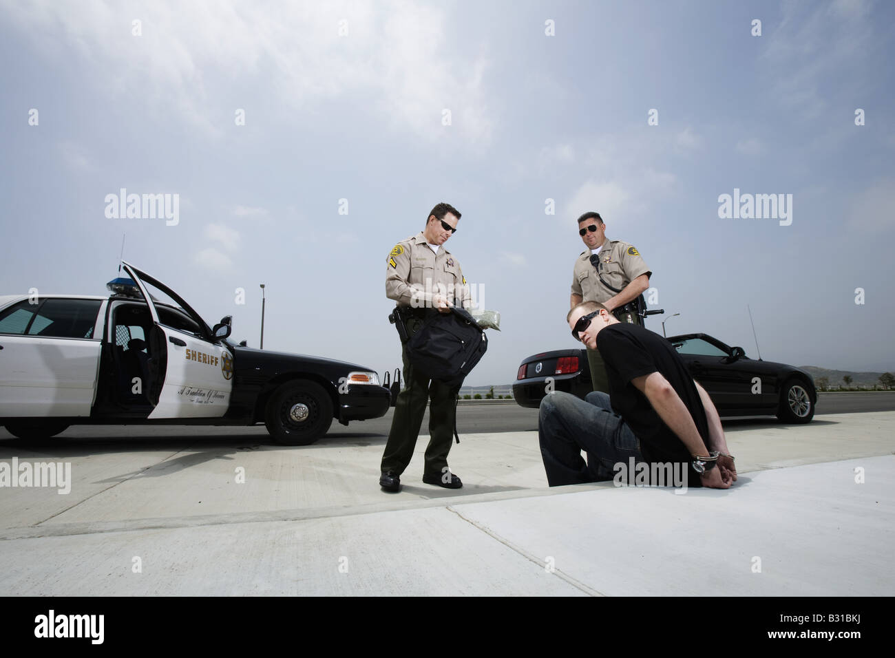 Two police officers discovering drugs in backpack of arrested man Stock ...