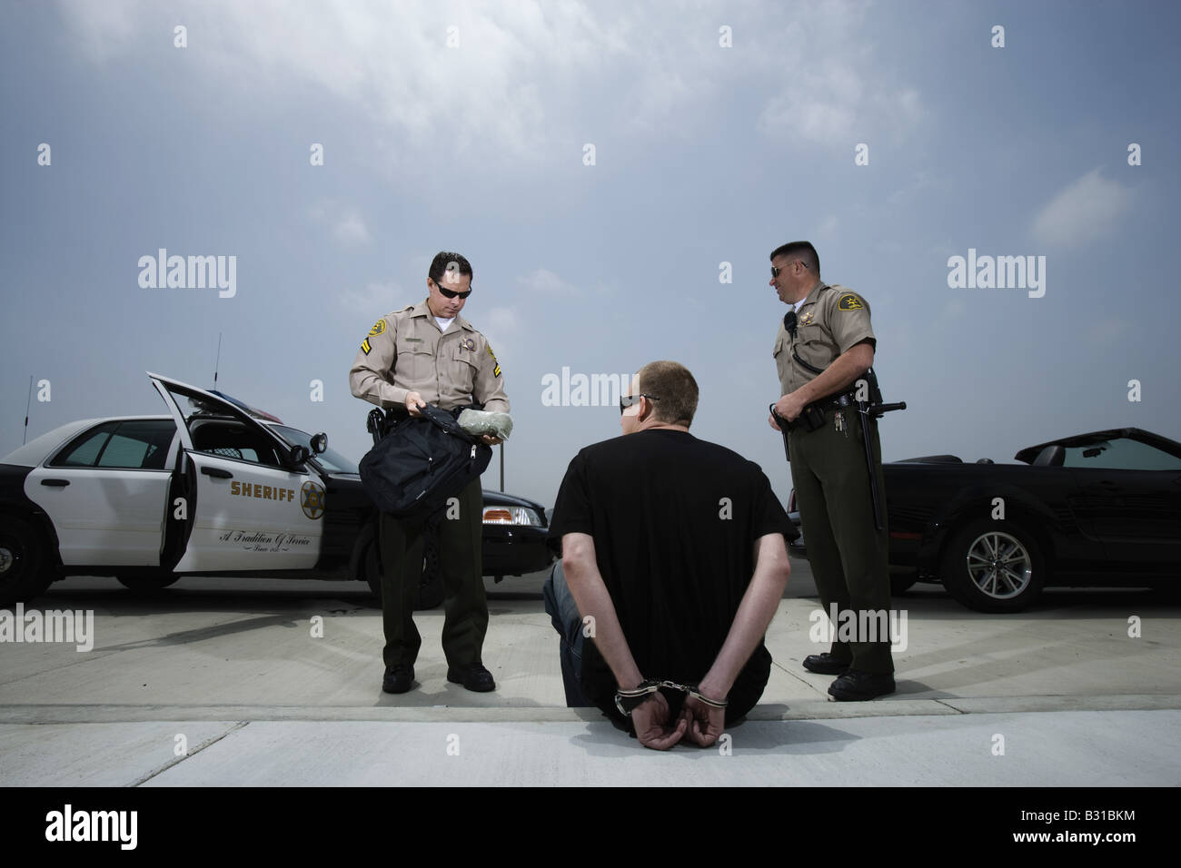 Two police officers discovering drugs in backpack of arrested man Stock ...