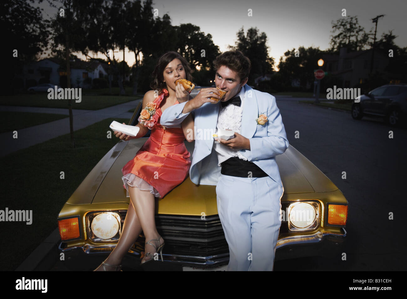 Prom goers sitting on car eating hot dogs Stock Photo - Alamy