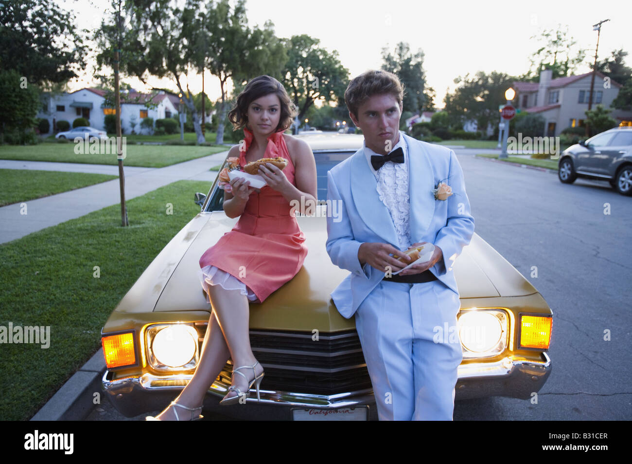 Prom goers sitting on car with hot dogs Stock Photo - Alamy