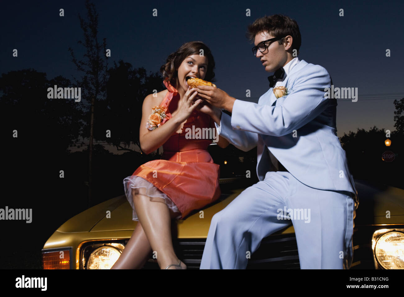 Prom goers sitting on car eating hot dogs Stock Photo - Alamy