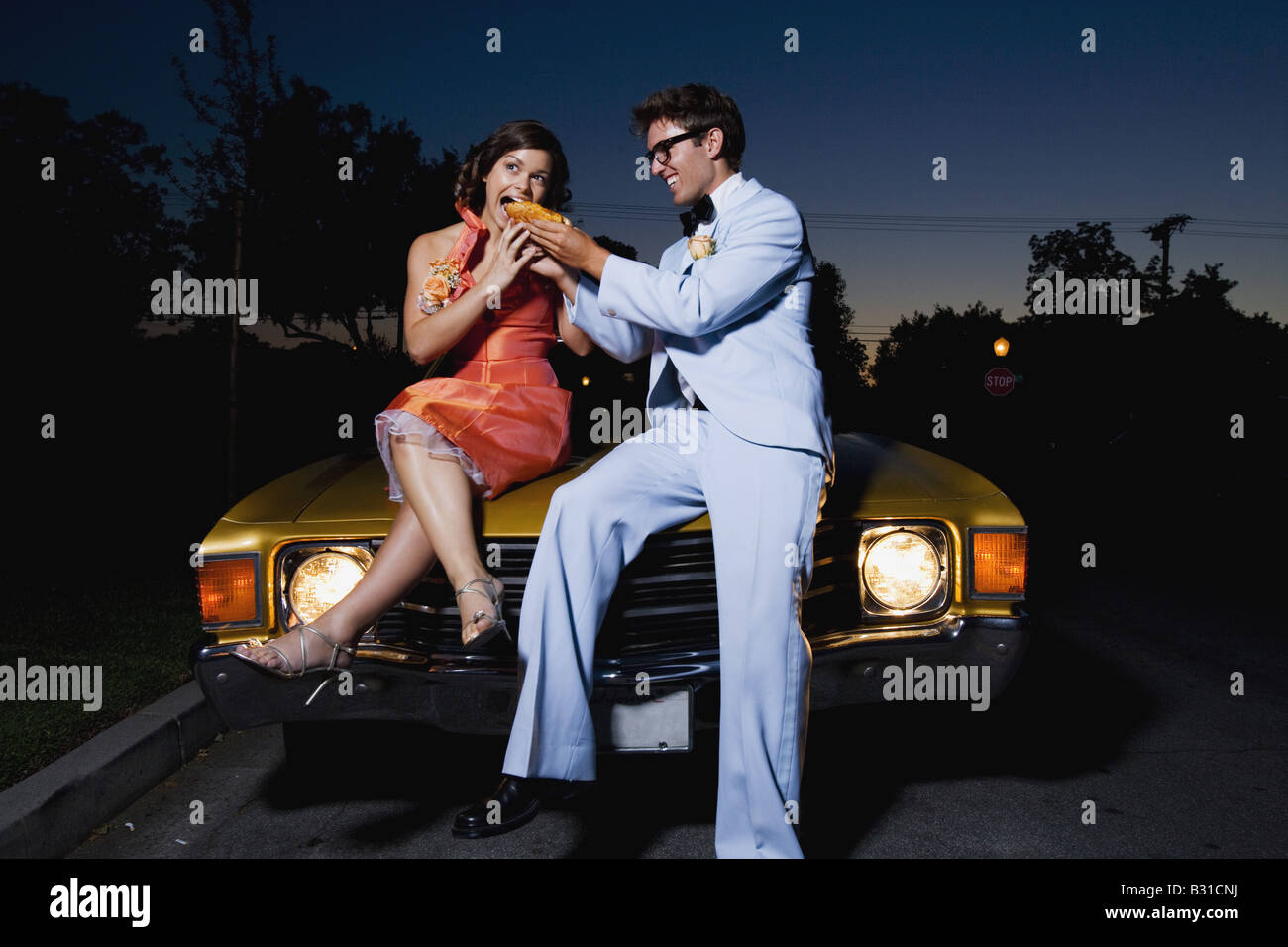 Prom goers sitting on car eating hot dogs Stock Photo - Alamy