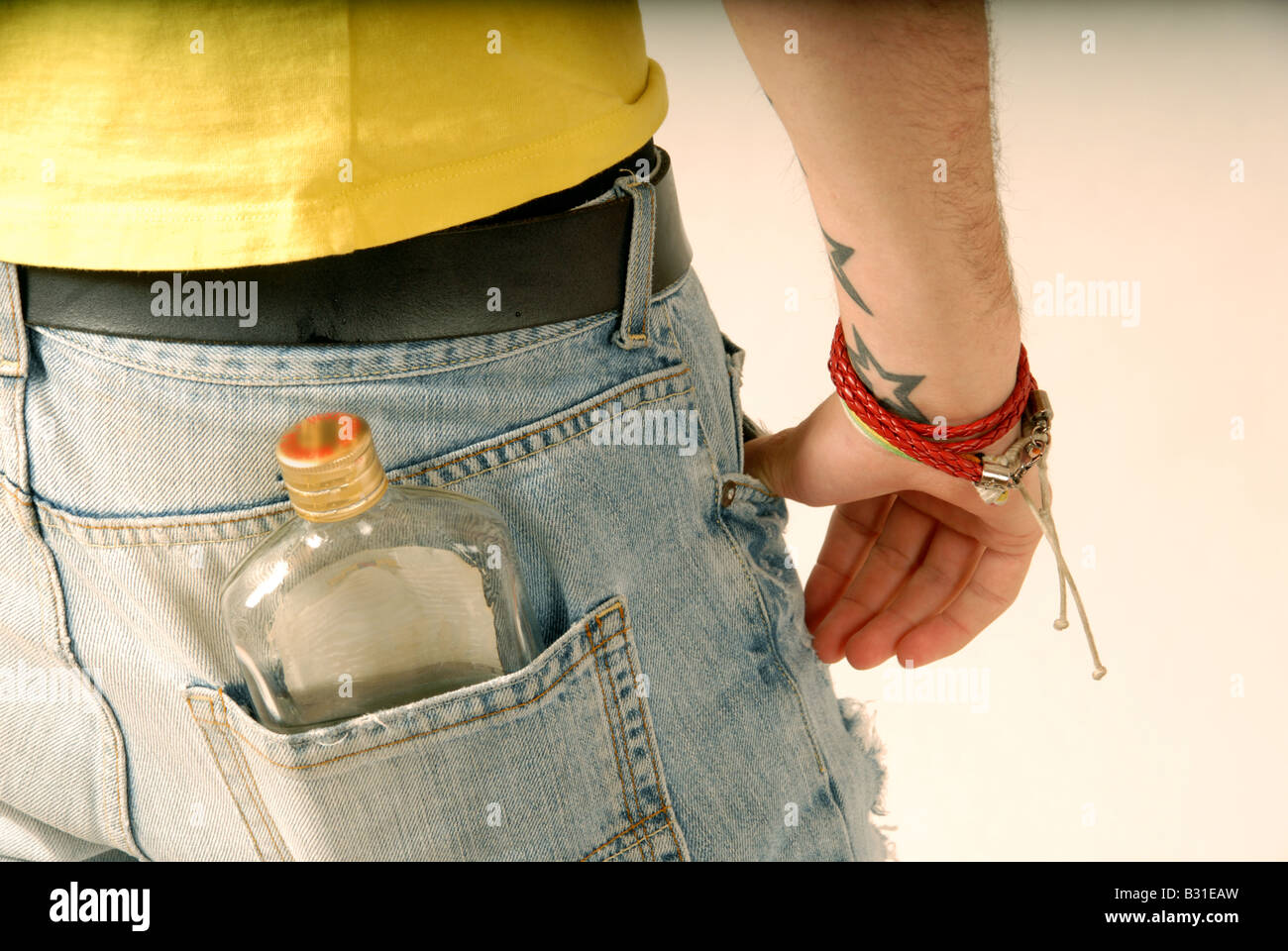 A young man with a bottle of alcohol sticking out of the back pocket of ...