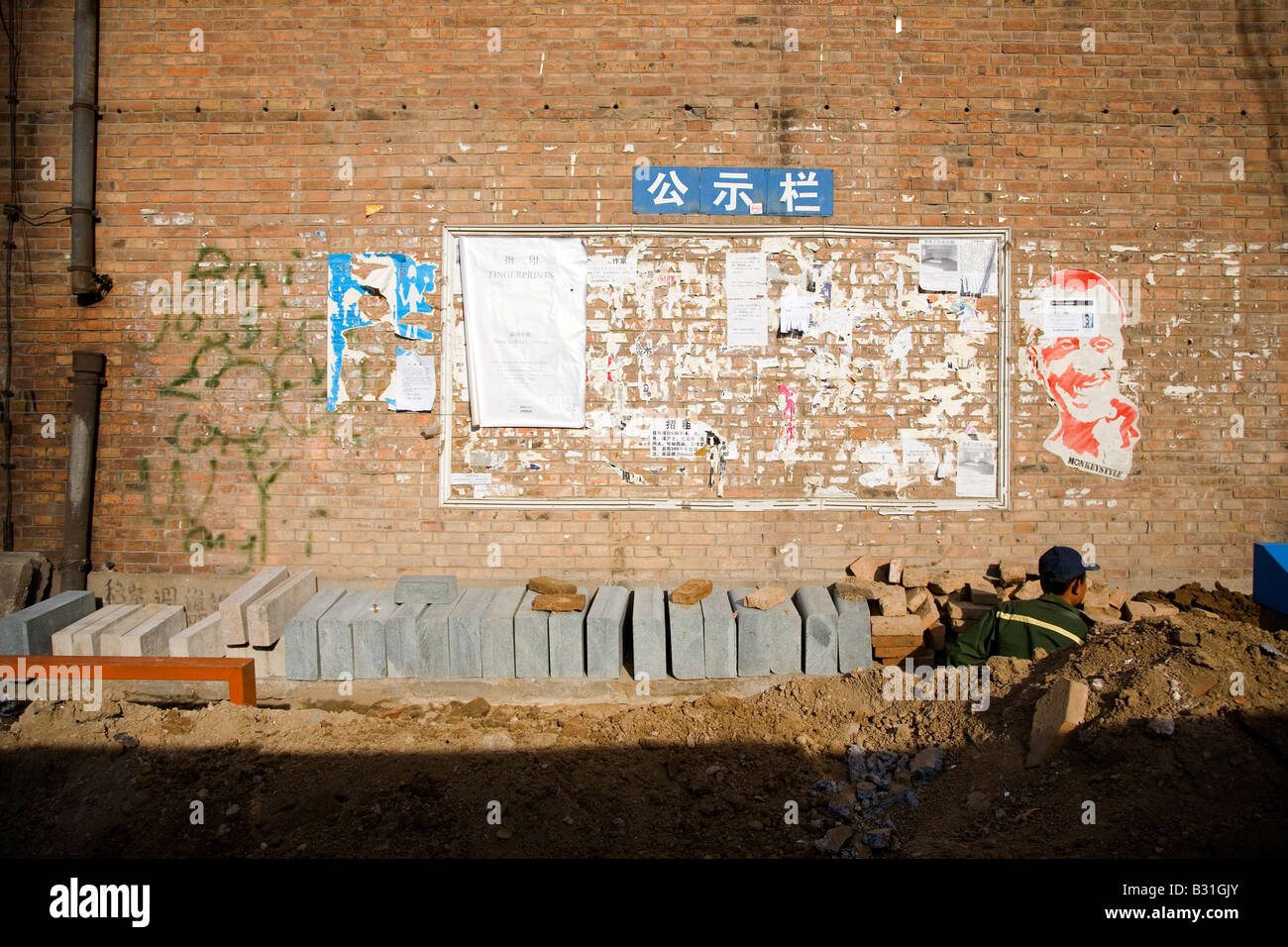 Chinese man digging a ditch next to a wall with grafitti Stock Photo ...