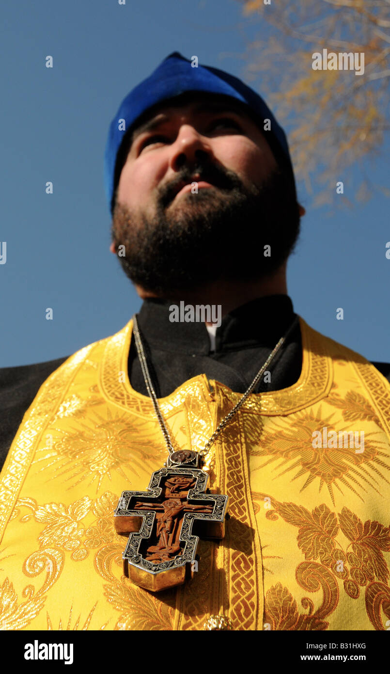 A brightly colored Greek Orthodox Priest, whilst watching over a mass ...