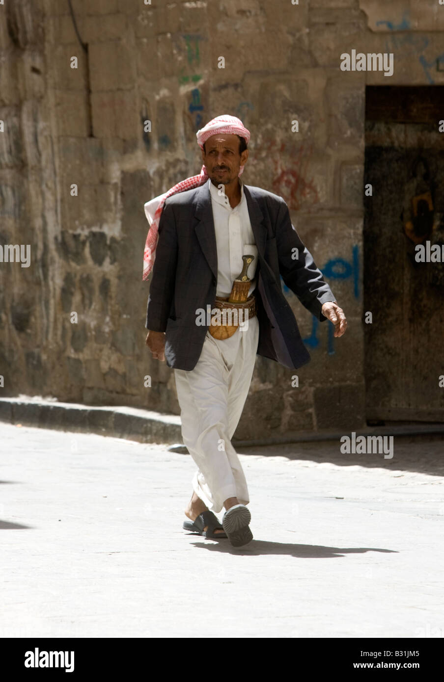 A old Muslim man from Yemen walking through Old Sanaa City wearing his ...