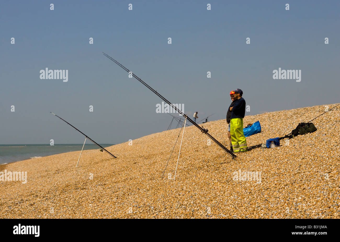 Sea anglers fishing from the shingle shoreline on Dungeness beach Stock ...