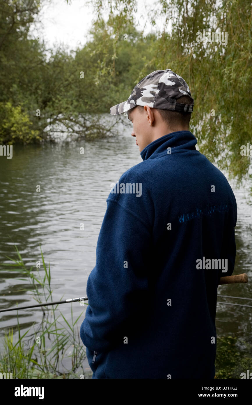 Young man fishing by the side of a lake Stock Photo - Alamy