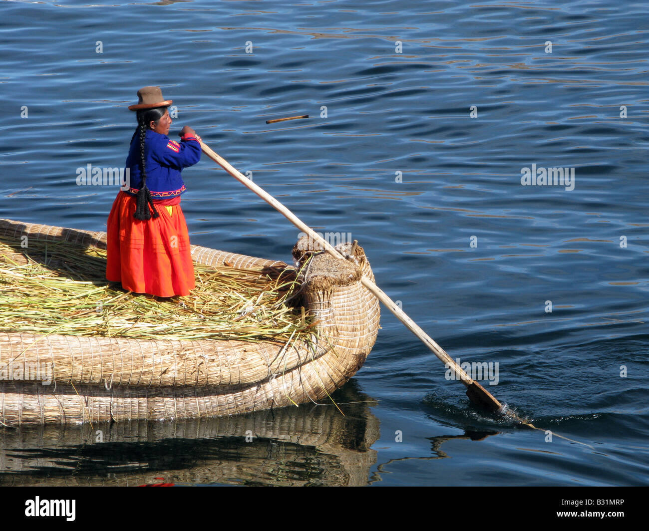 A female member of the Uros people rowing a boat on Lake Titicaca, Peru ...