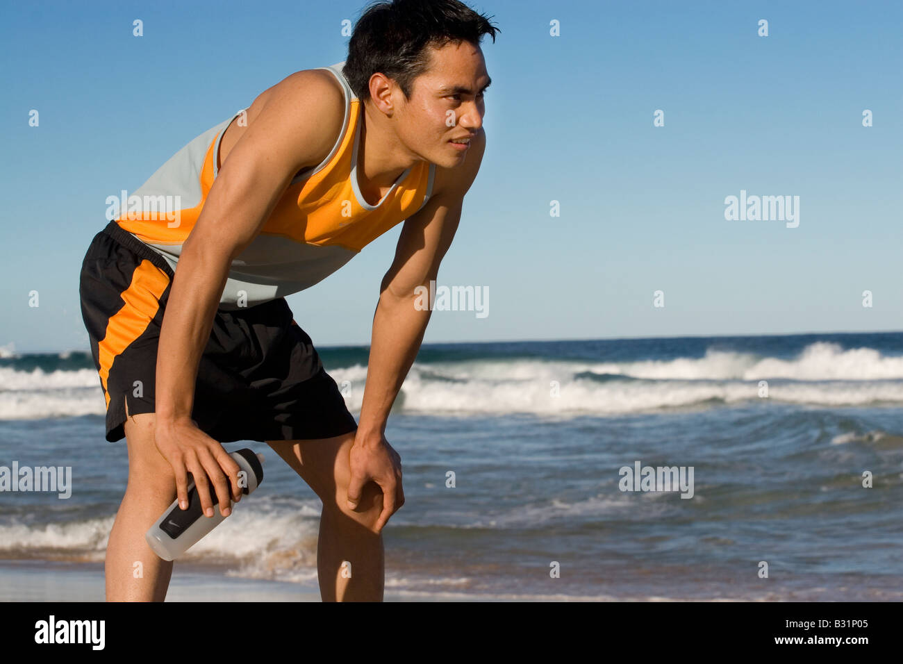 Male Runner Pausing for Breath on Beach Stock Photo - Alamy