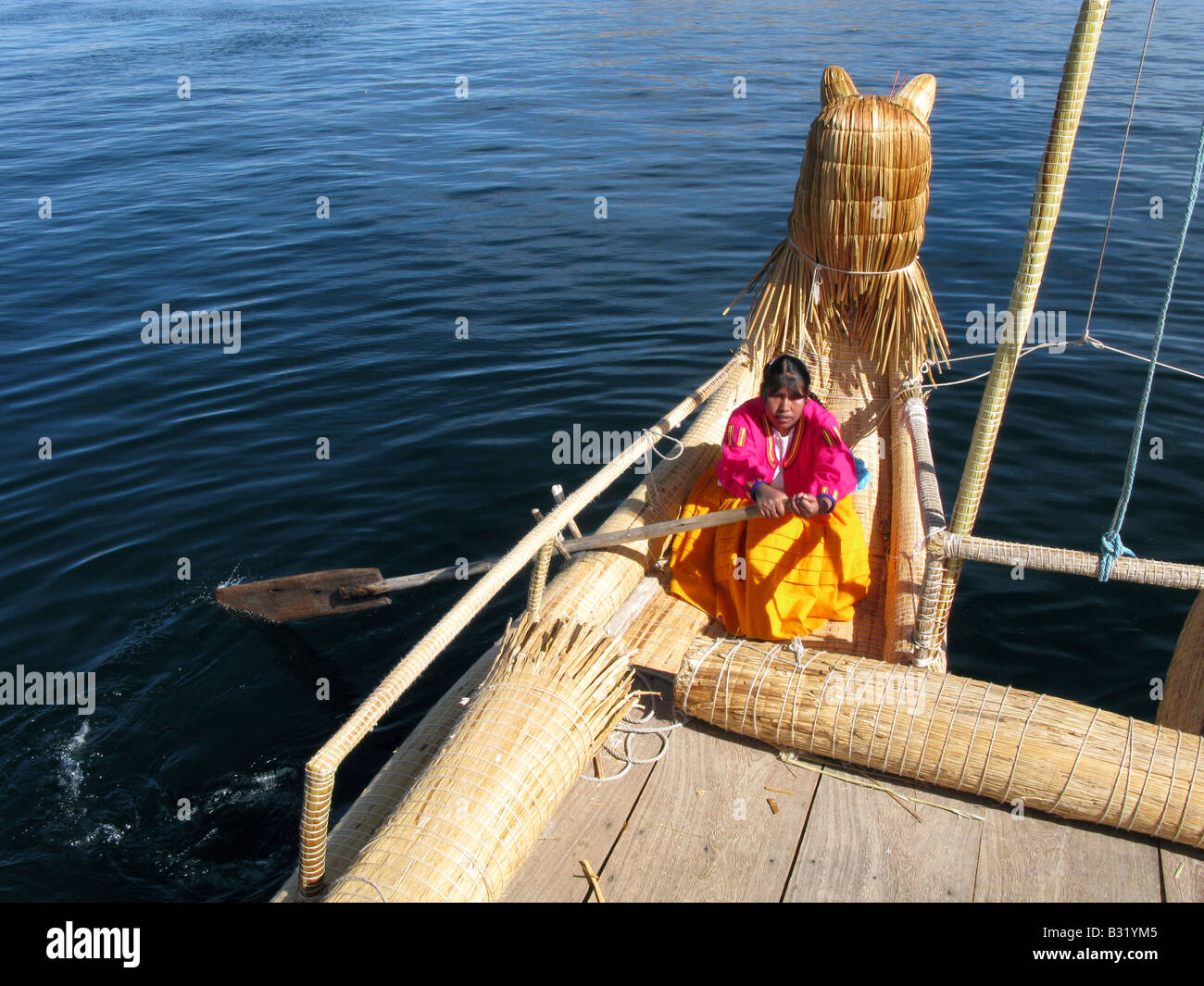 A member of the Uros people rowing a boat on Lake Titicaca, Peru, South ...