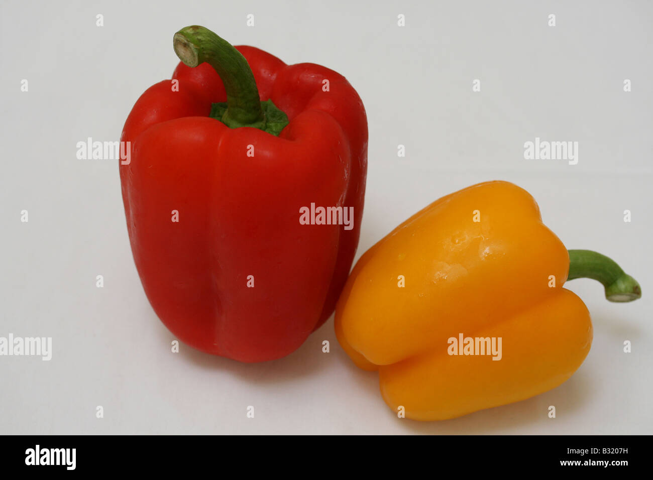 A red and yellow pepper against a white background Stock Photo - Alamy