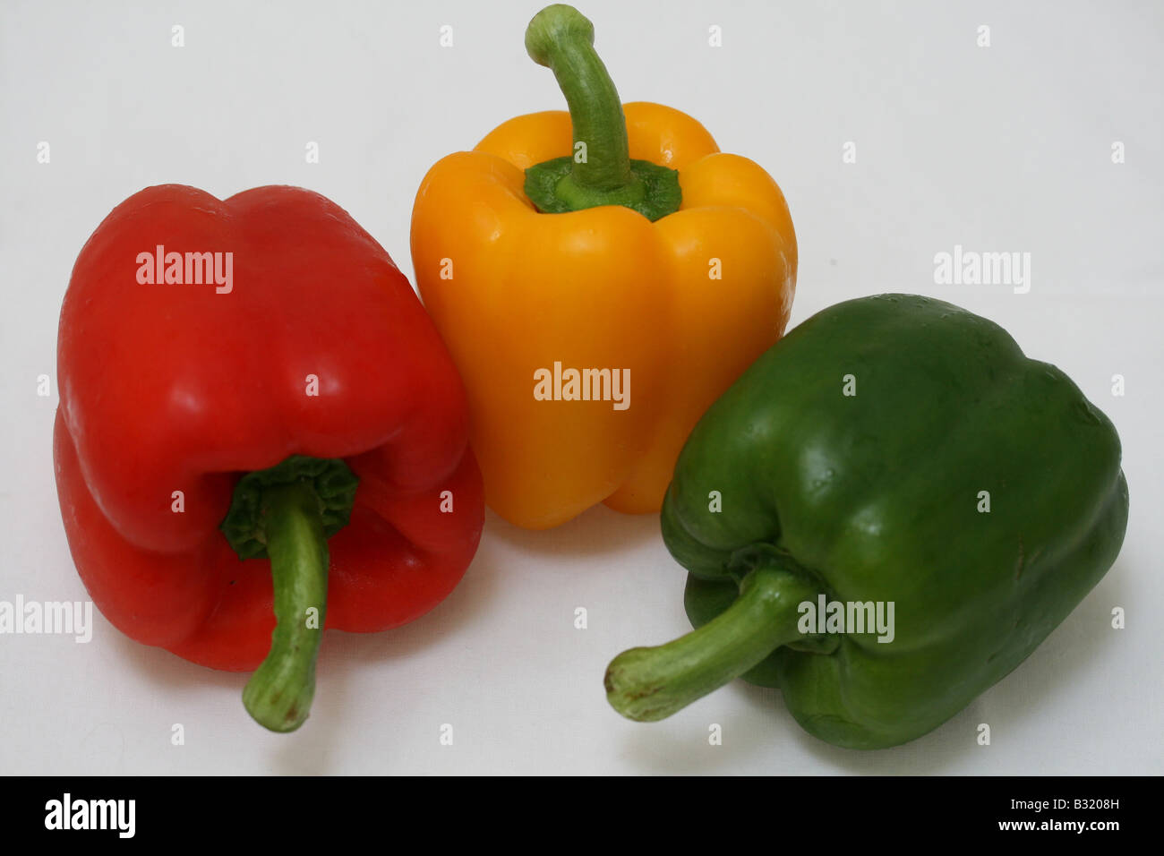 A group of red, yellow and green capsicums against a white background ...