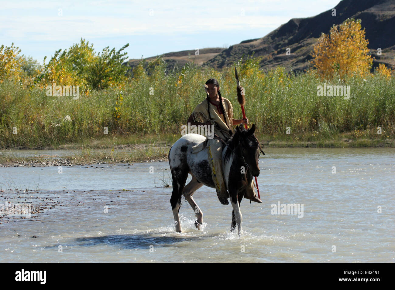 A Native American Sioux Indian on horseback riding across a stream in ...