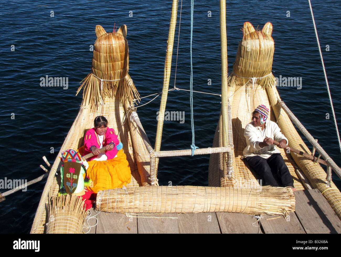Two members of the Uros people rowing a boat on Lake Titicaca, Peru ...