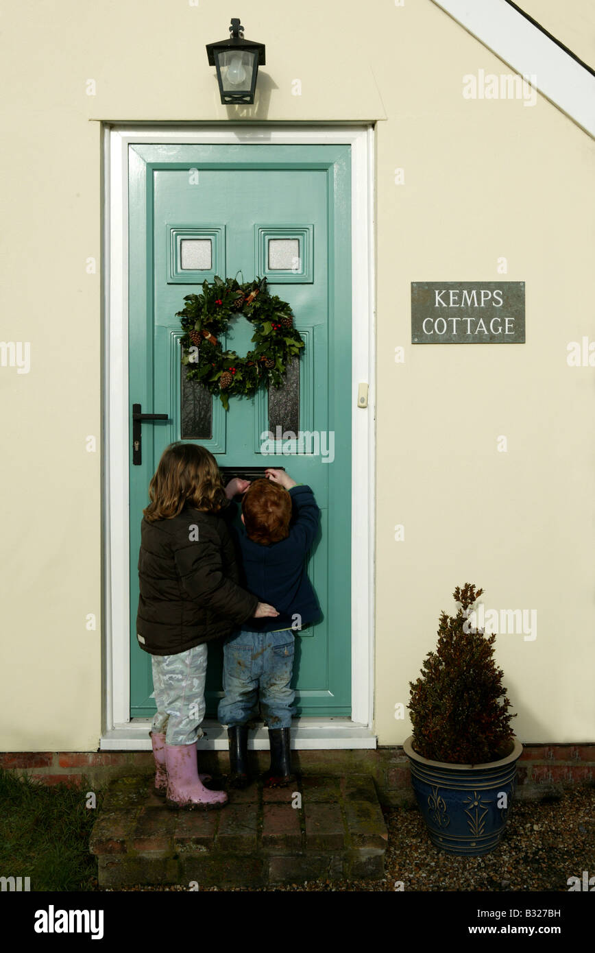 two young children posting a letter into the letter box of a country ...