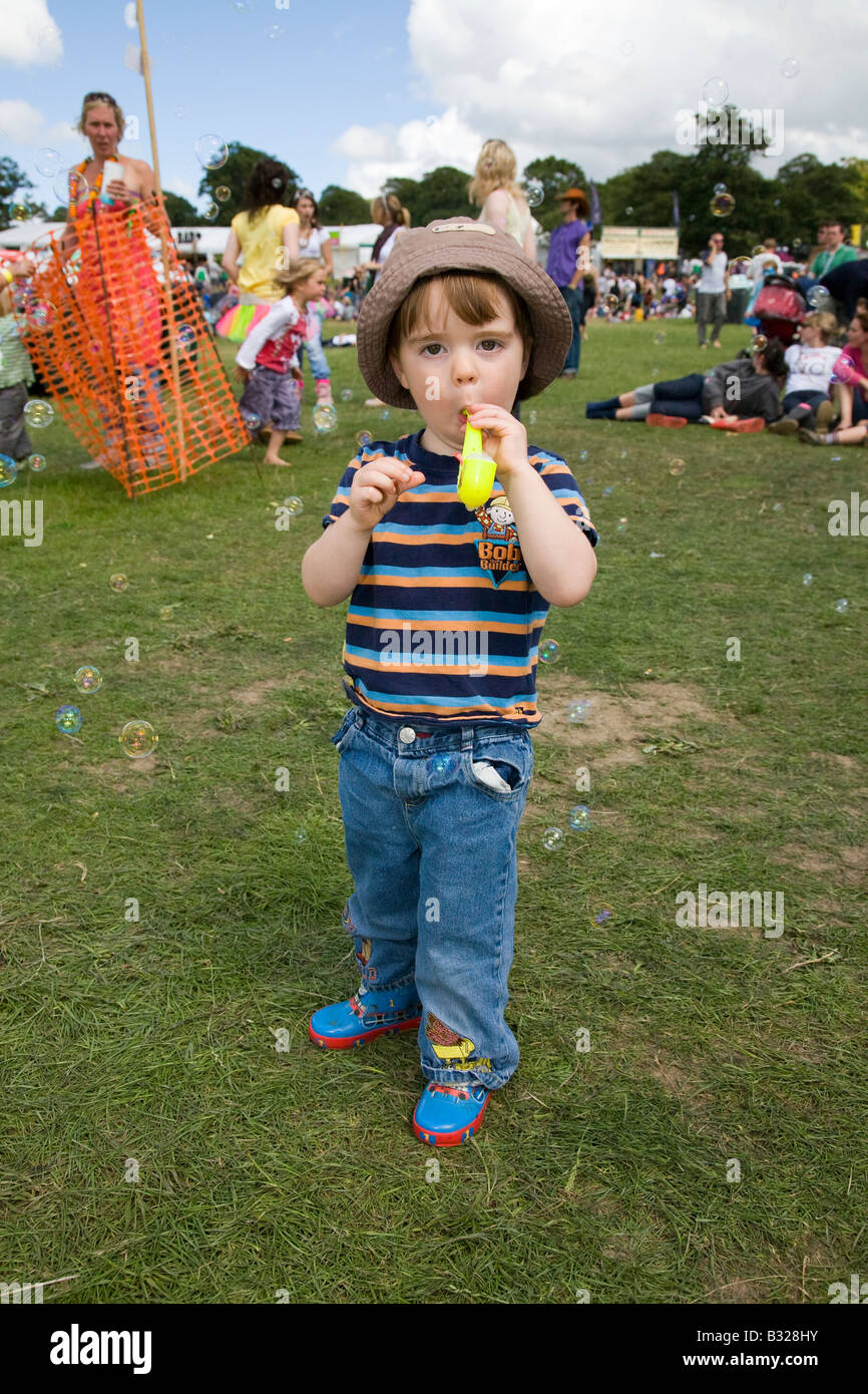 Boy blowing bubbles through a toy bubble-pipe in the sunshine at the ...