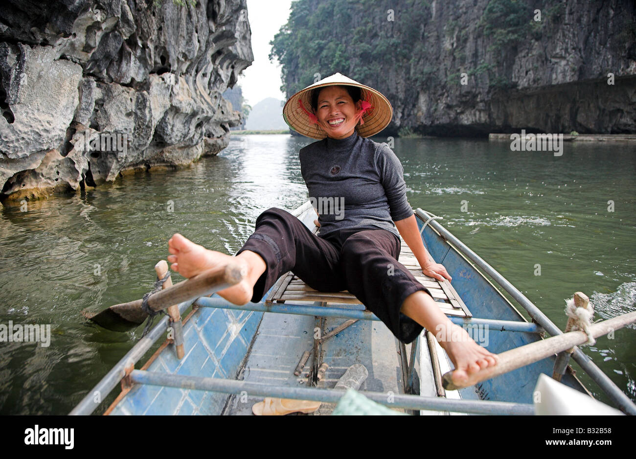 A vietnamese woman rowing the baot with her feet on the Ngo Dong River ...