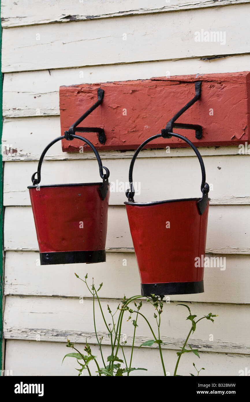 Red fire buckets hanging from brackets on a wood wall Stock Photo - Alamy