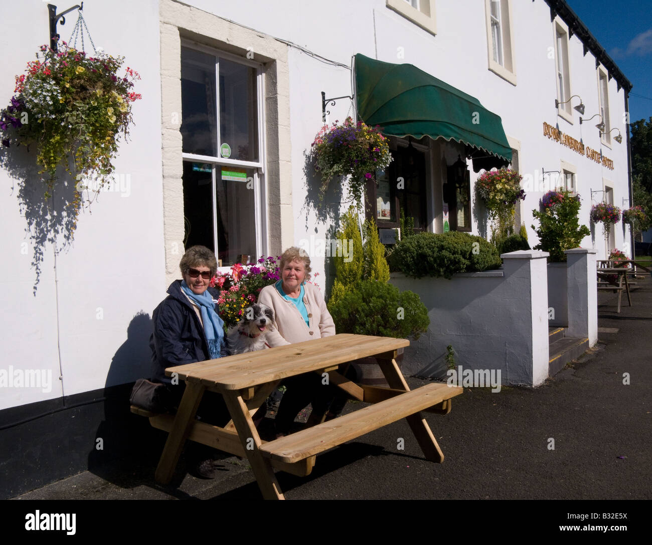 English ladies with dog resting outside a pub in Craster ...