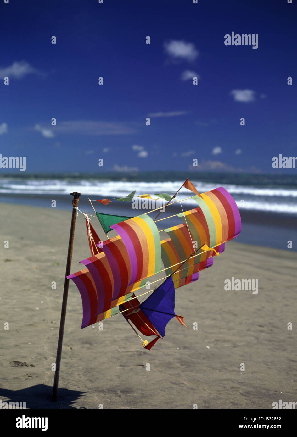 Beach Sand Sea Large waves Bright coloured kite tied to pole Wind ...