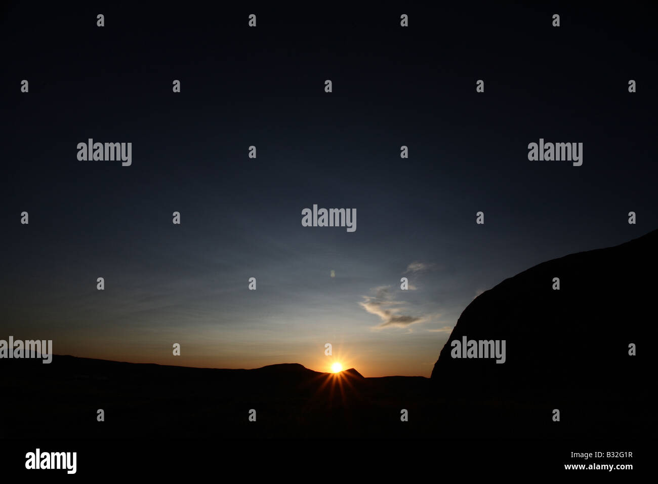 Sun setting behind a rise Stock Photo - Alamy