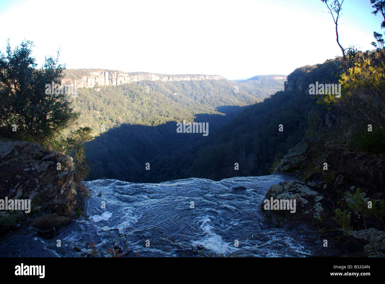 Waterfall drop off overlooking lush green valley on sunny day contrast ...