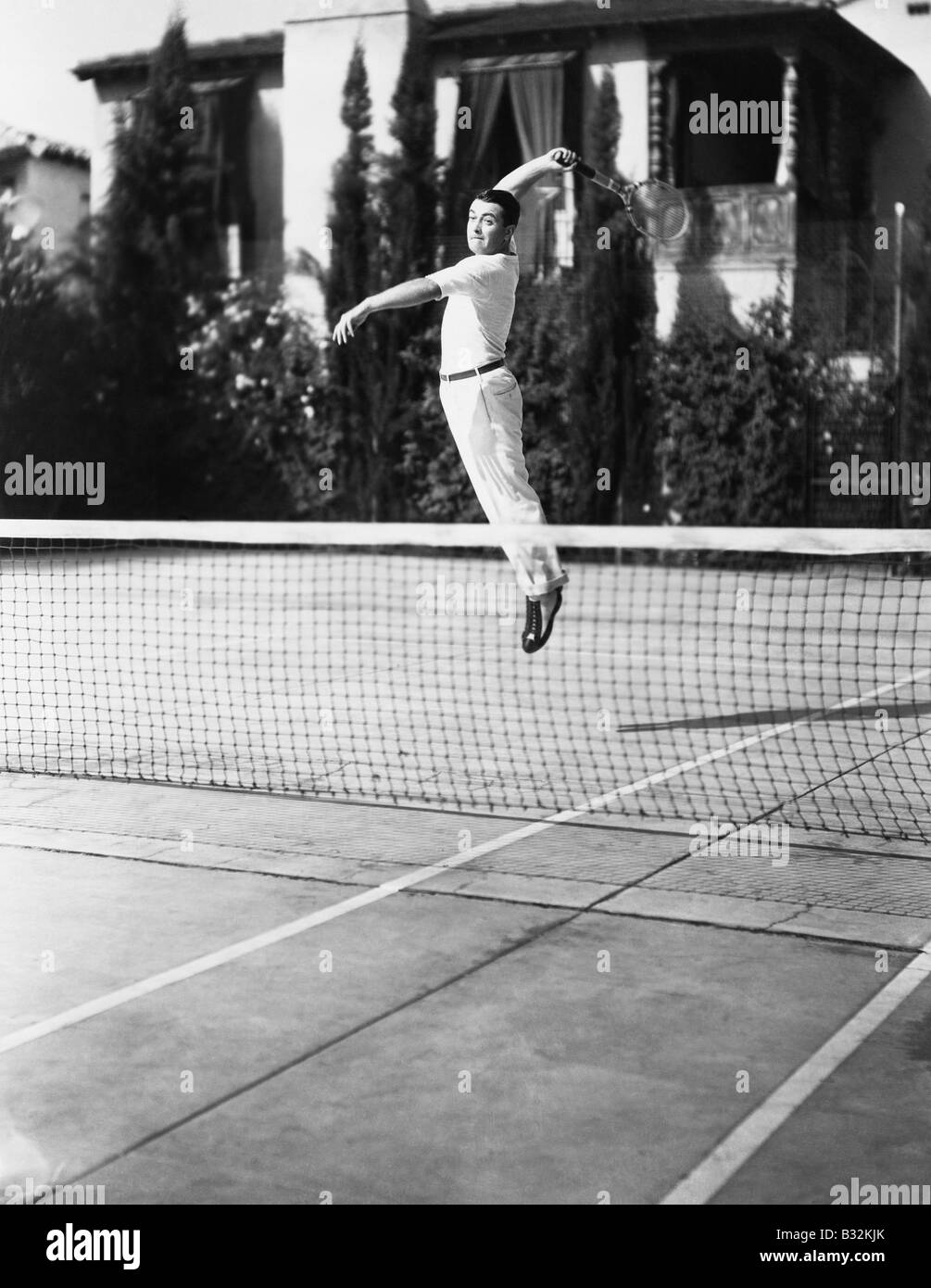 Male tennis player jumping for shot Stock Photo - Alamy