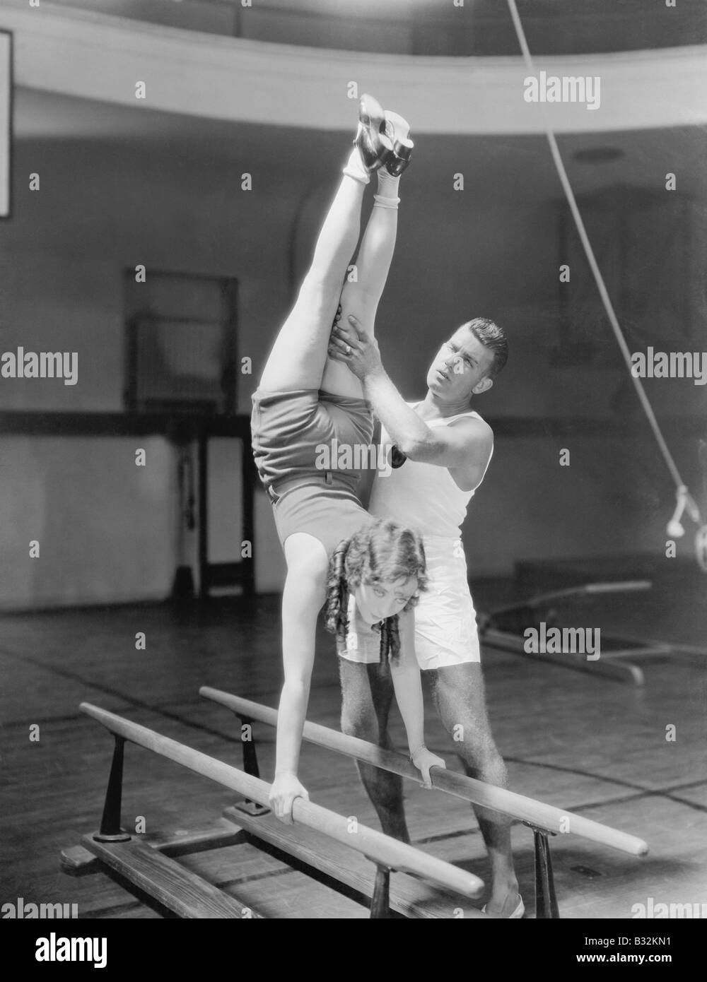 Coach helping woman on parallel bars Stock Photo - Alamy