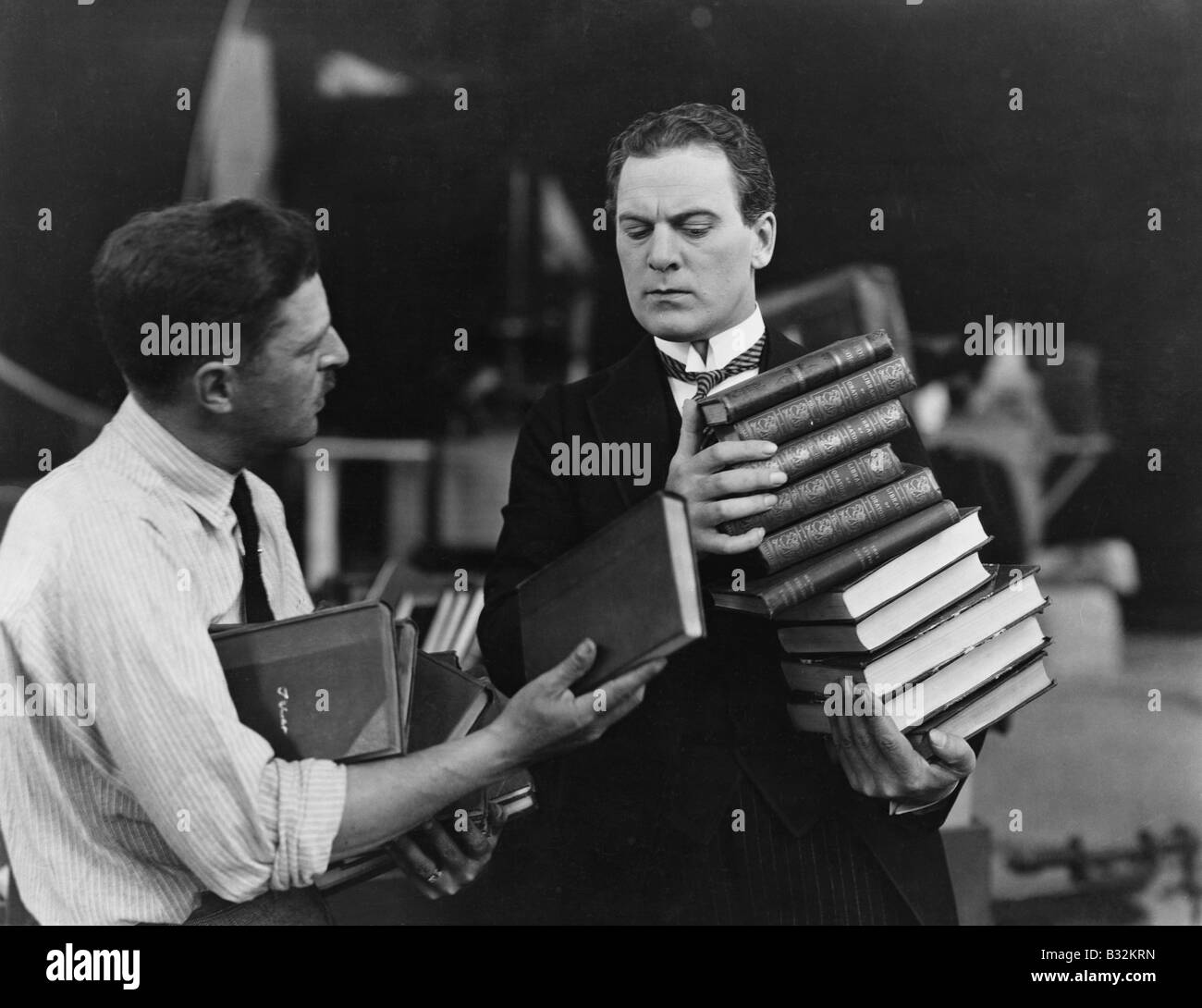 Men with stacks of books Stock Photo - Alamy