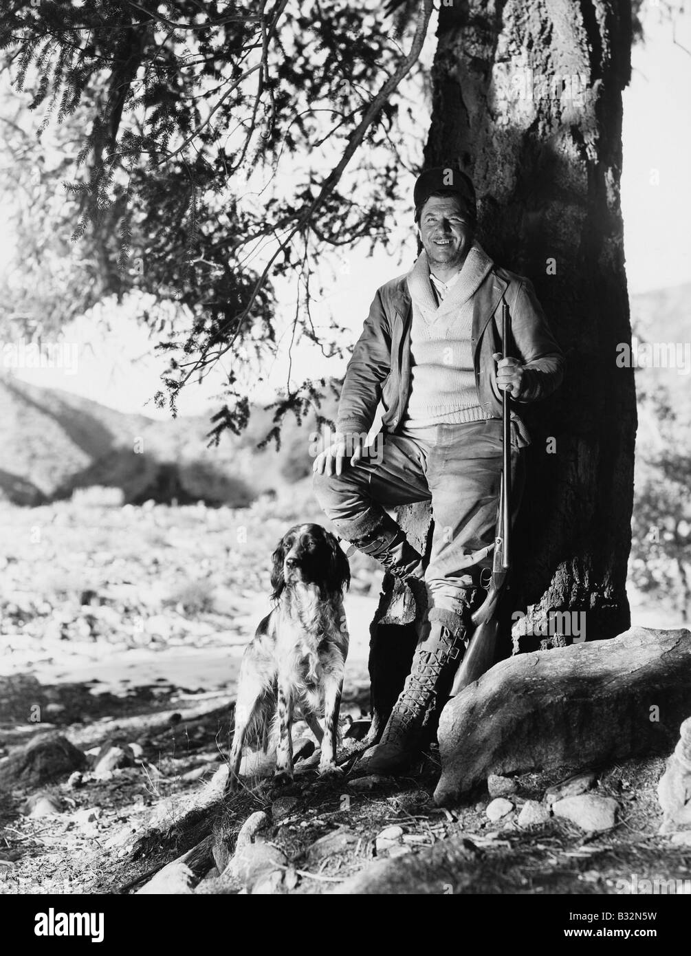 Portrait of hunter and dog under tree Stock Photo - Alamy