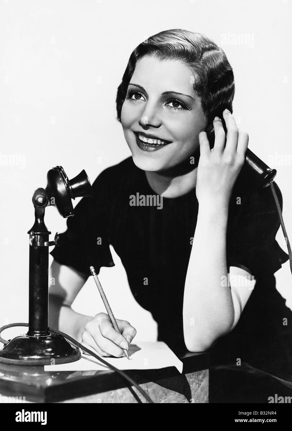 Smiling woman using telephone Stock Photo - Alamy