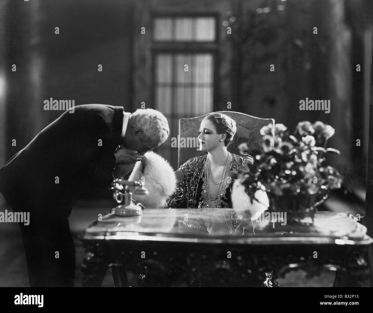 Man kissing hand of woman sitting at desk Stock Photo - Alamy