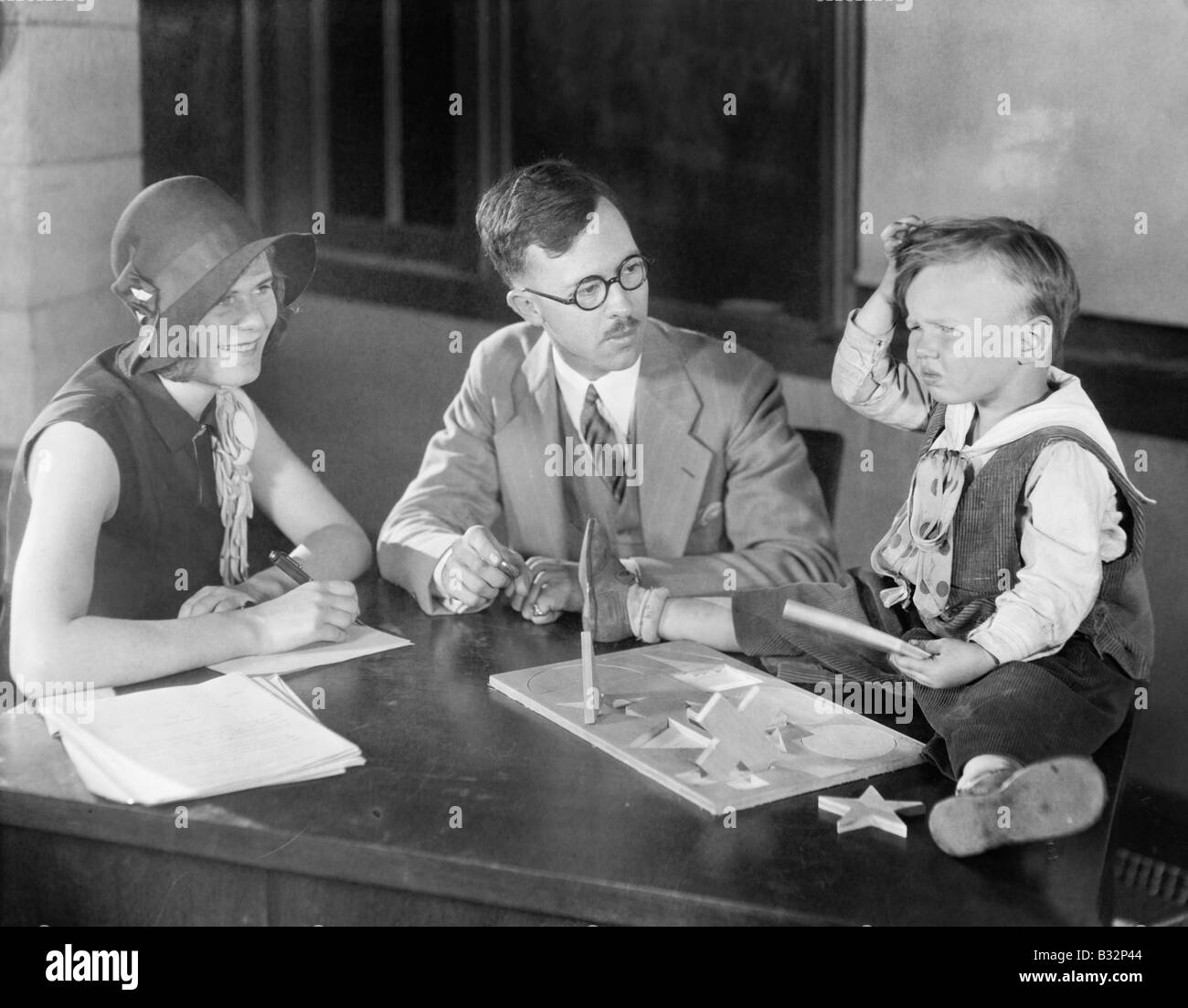 Adults testing little boy doing puzzle Stock Photo - Alamy