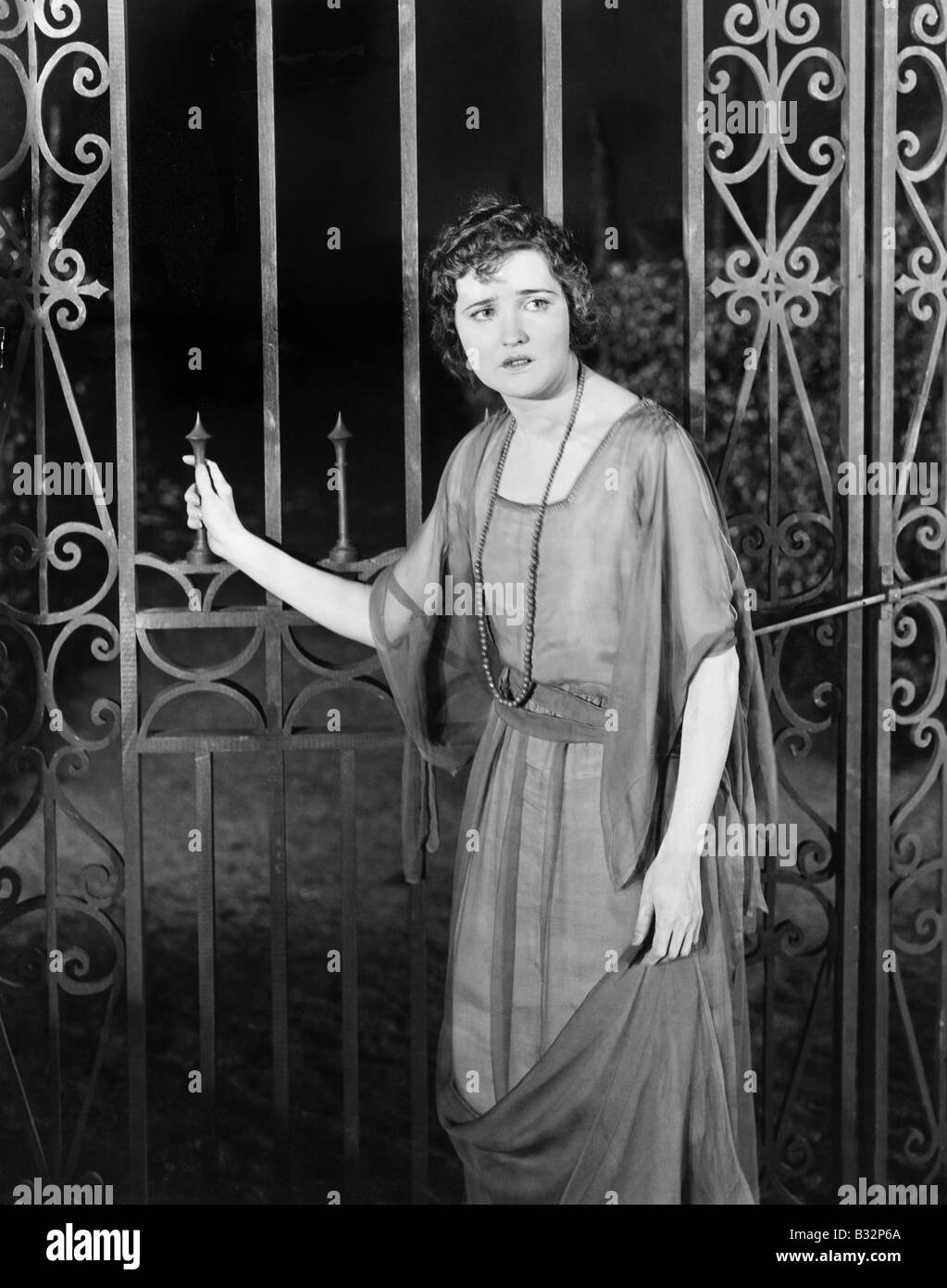 Worried woman at gate Stock Photo - Alamy