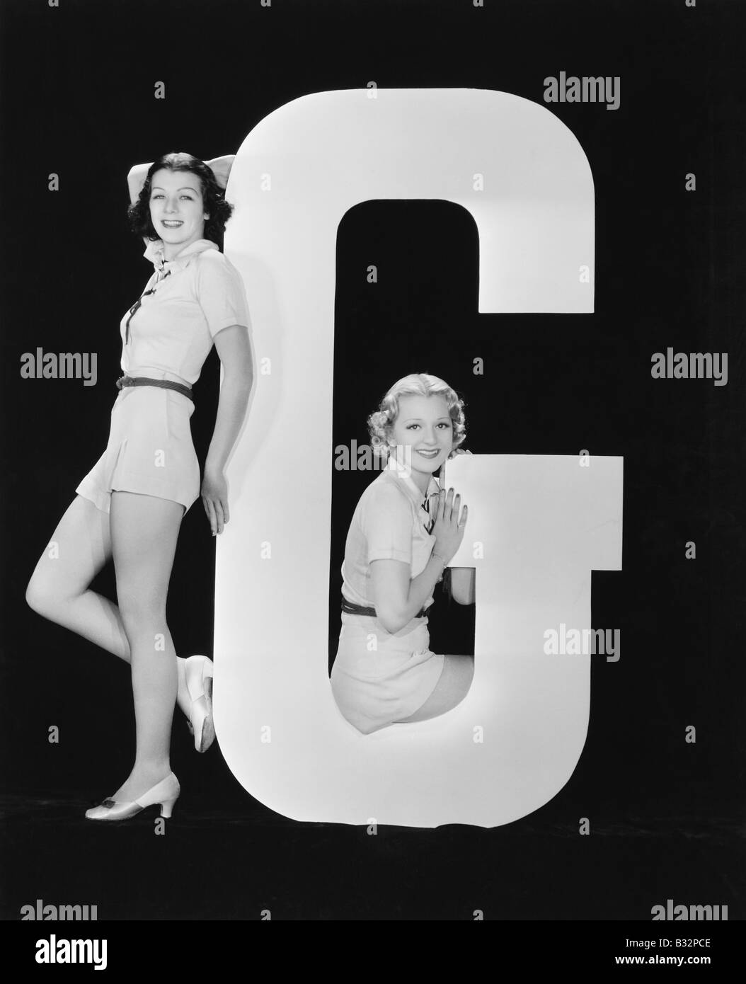Women posing with huge letter G Stock Photo - Alamy