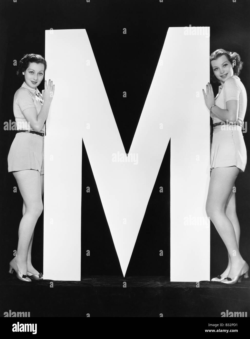 Two women posing with huge letter M Stock Photo - Alamy
