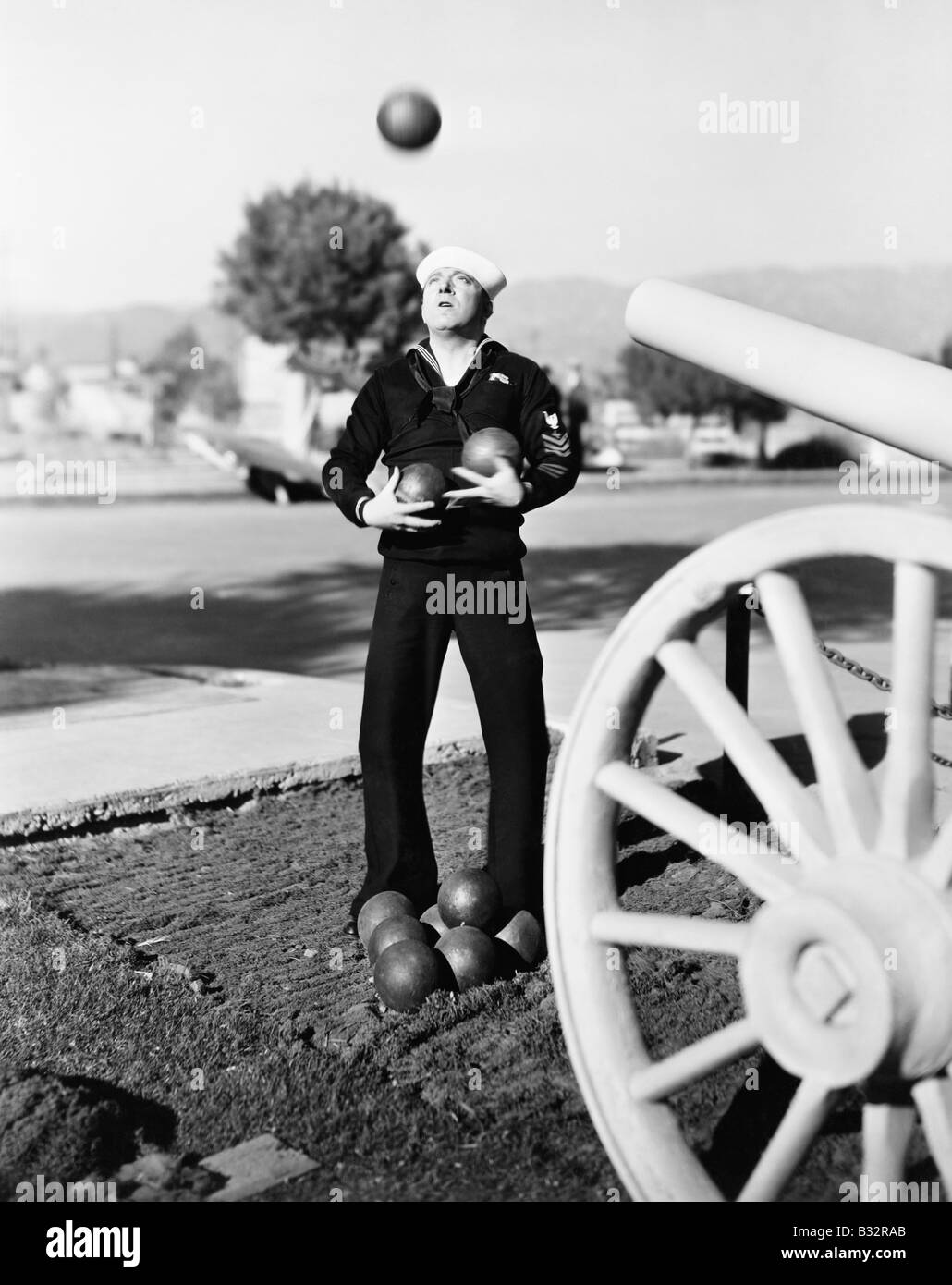 Man in sailors uniform trying to juggle cannon balls Stock Photo - Alamy