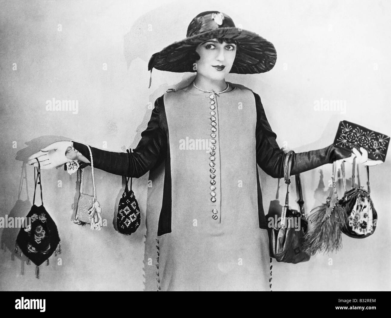 Woman standing with her arms apart wearing handbags Stock Photo - Alamy