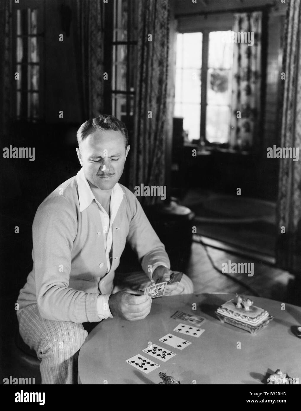 Man sitting in his living room playing cards Stock Photo - Alamy