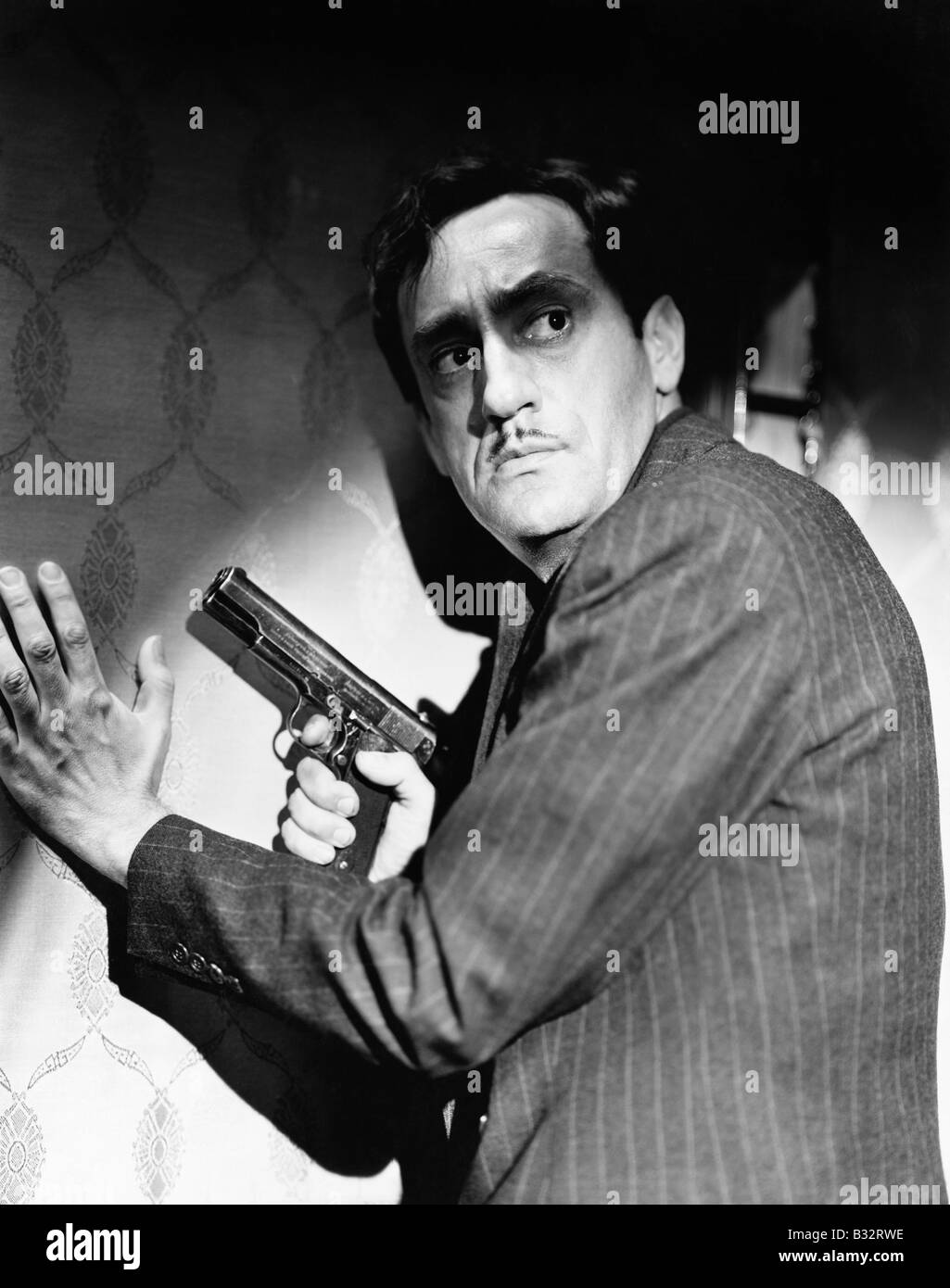 Profile of a gangster holding a handgun looking over his shoulder Stock ...