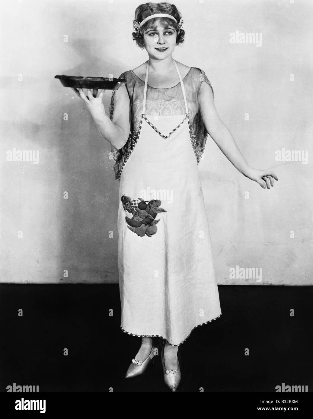 Woman in an apron holding a plate of food and smiling Stock Photo - Alamy