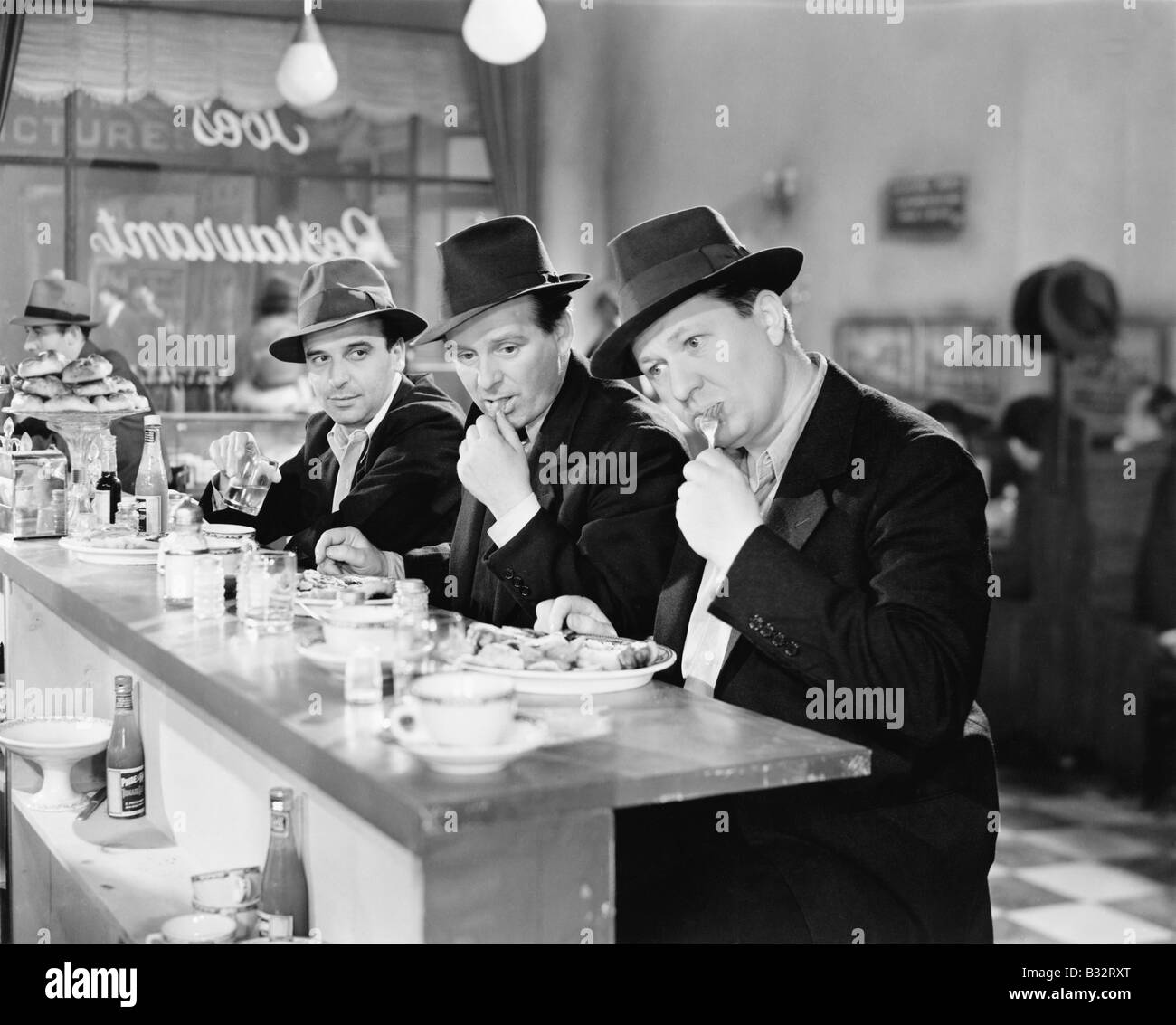 Three men with hats eating at the counter of a diner Stock Photo - Alamy