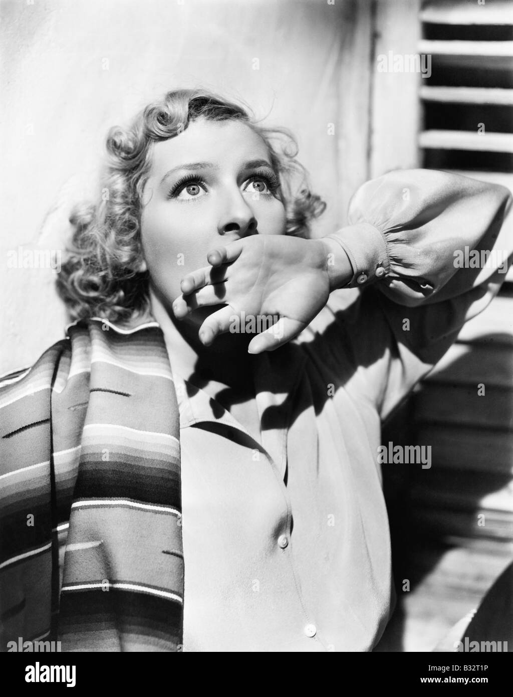 Portrait of a young woman looking in fear with her hand over her mouth ...