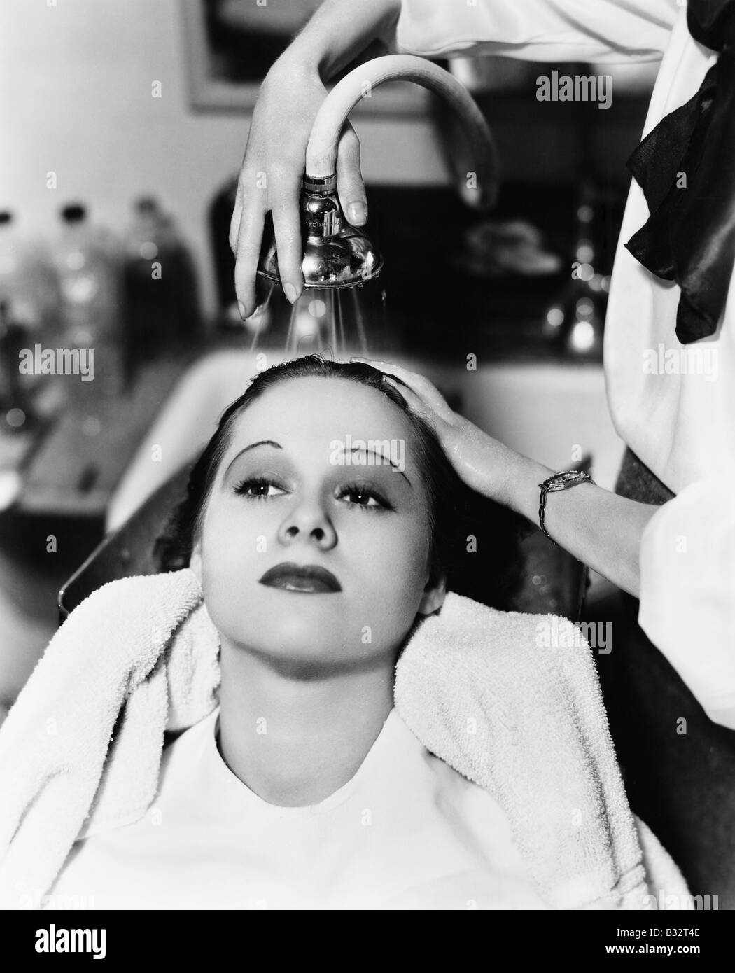 View of a female hairdresser washing hair of a young woman in a hair ...