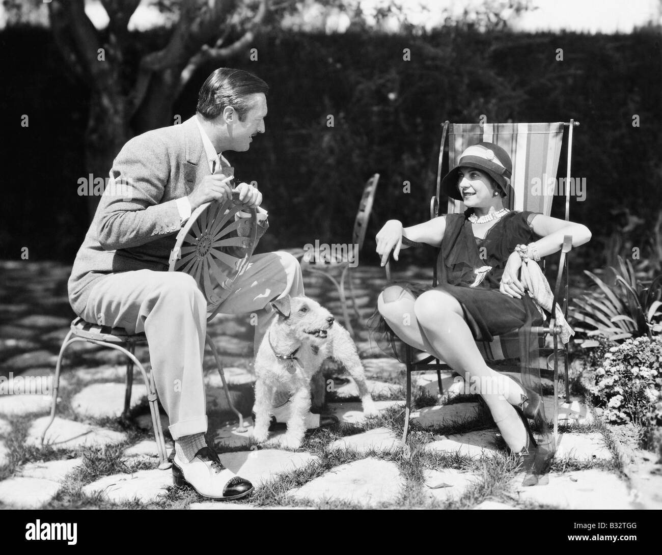 Couple sitting in the back yard talking with a dog between them Stock ...