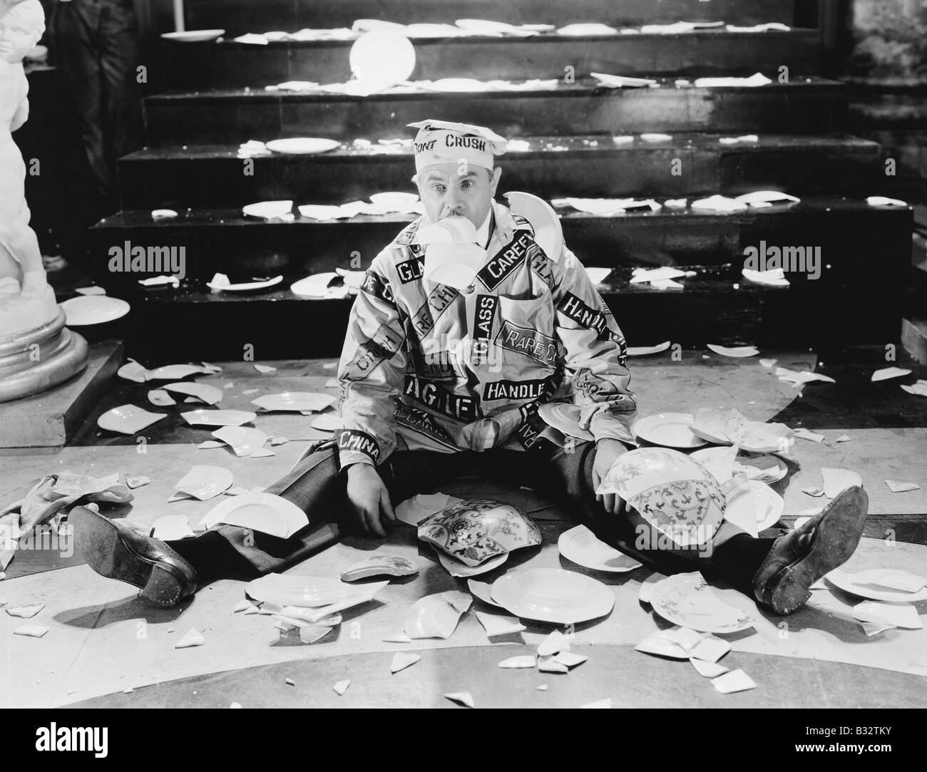 Man sitting in front of a staircase with broken plates around him Stock ...