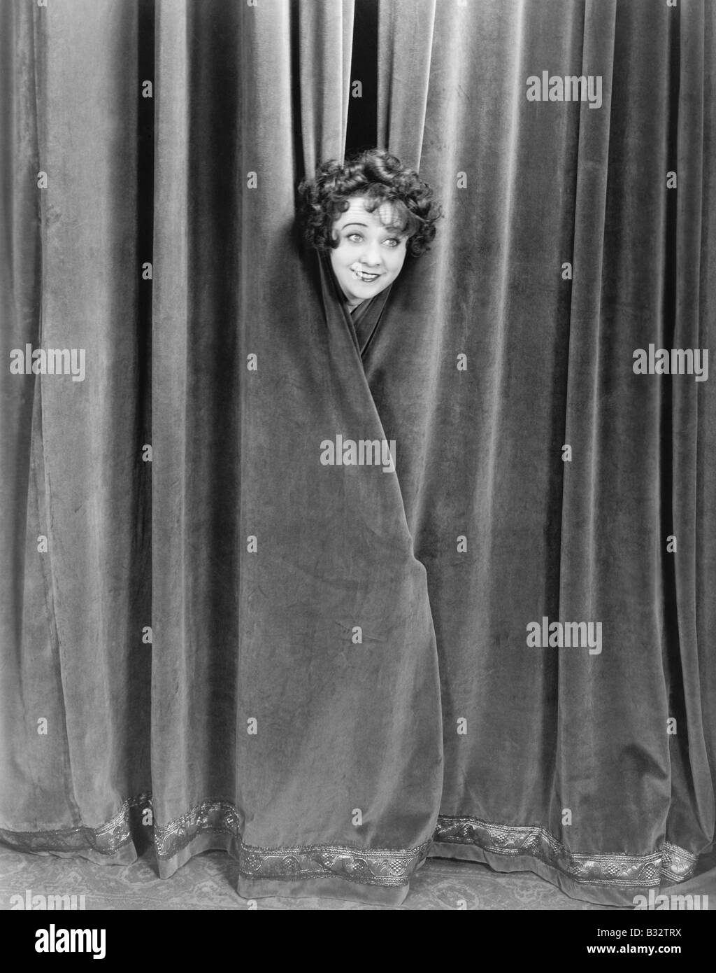 Woman peek-a-booing behind a curtain Stock Photo - Alamy