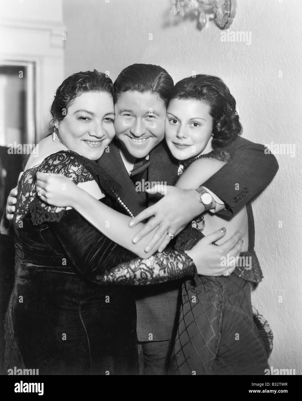 Three people embracing and laughing Stock Photo - Alamy