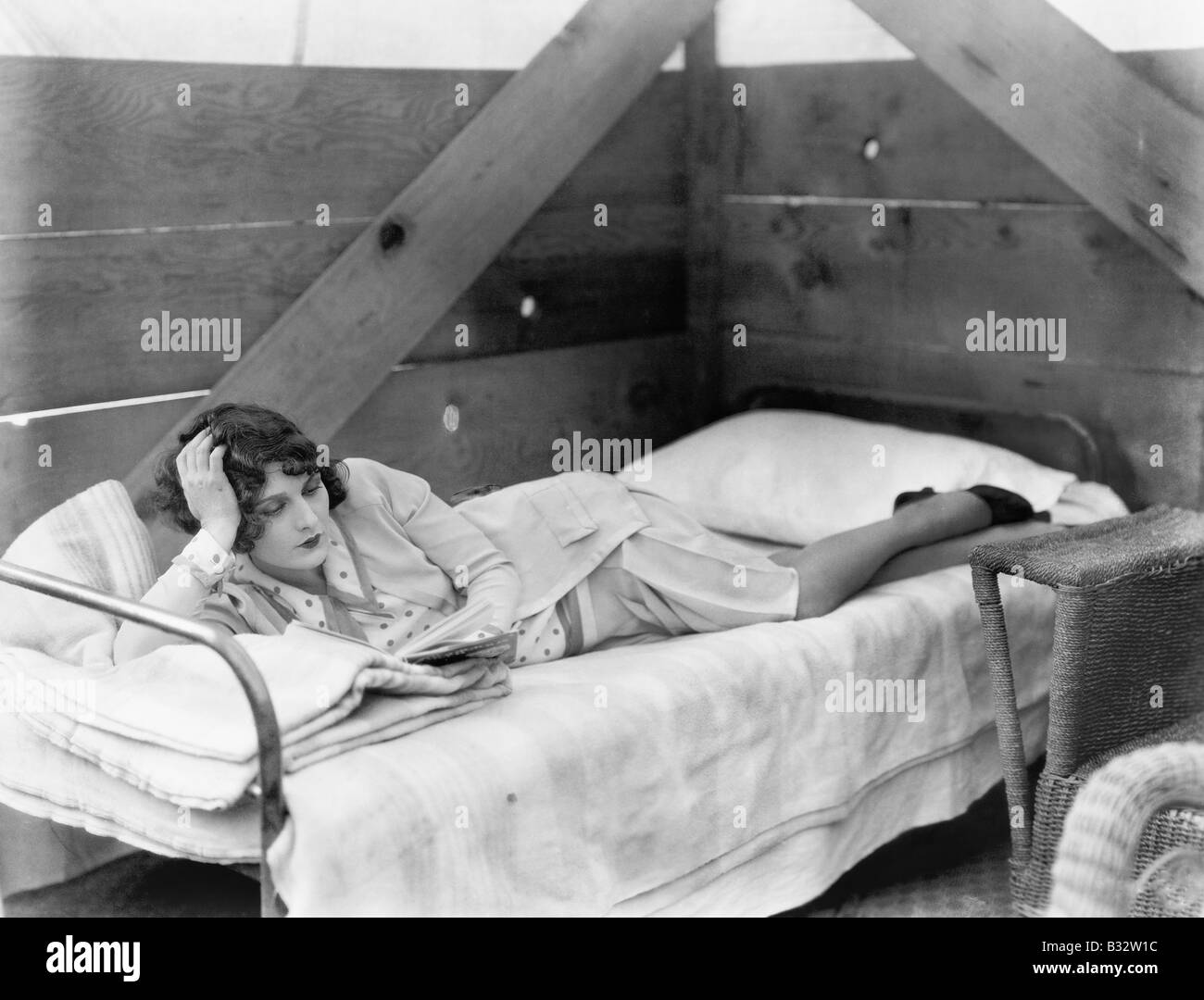 Woman stretched out on a cot reading a book Stock Photo - Alamy